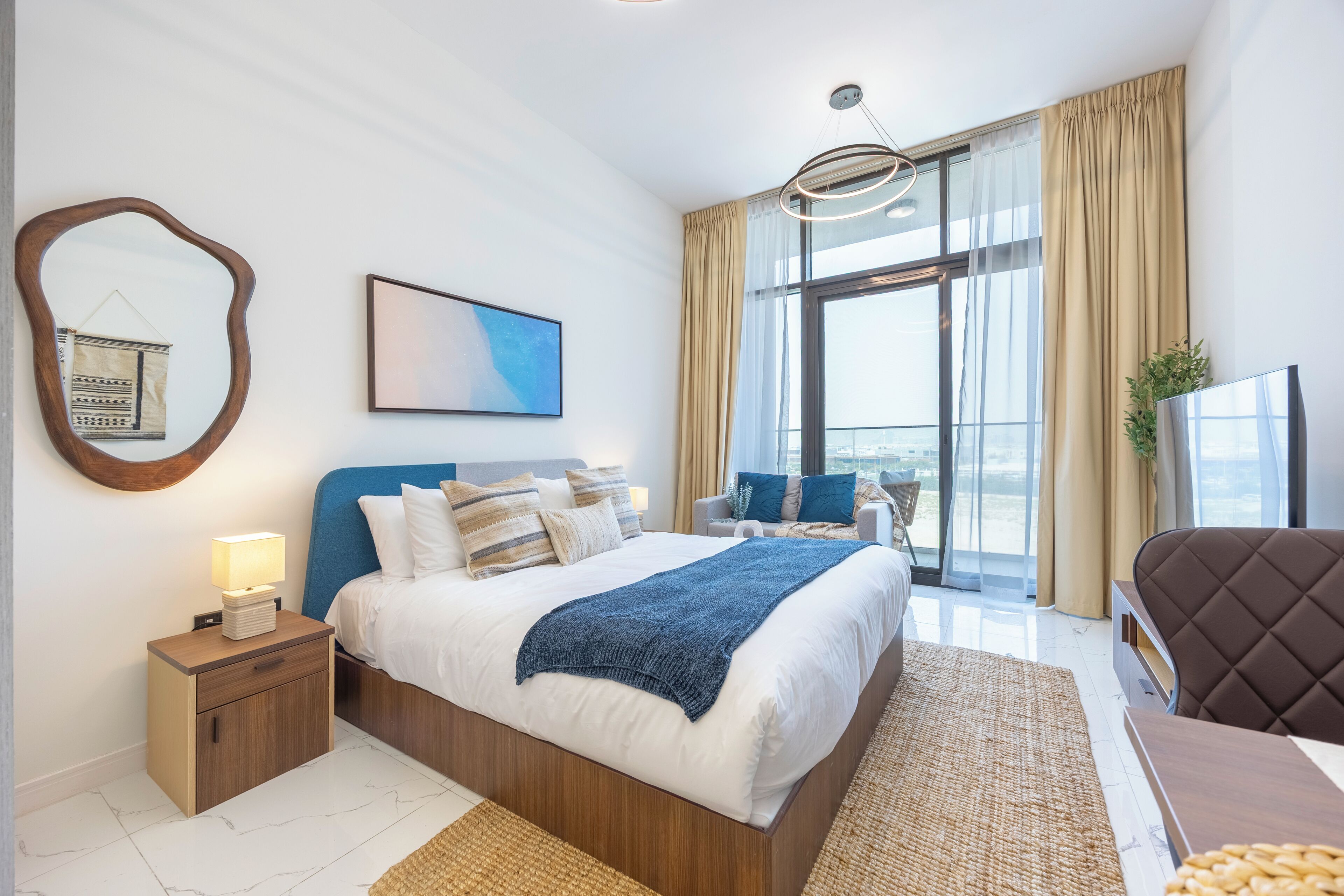 Quarto de hotel moderno com uma cama grande, uma mesinha de cabeceira, uma cadeira, televisão e varanda com vista.