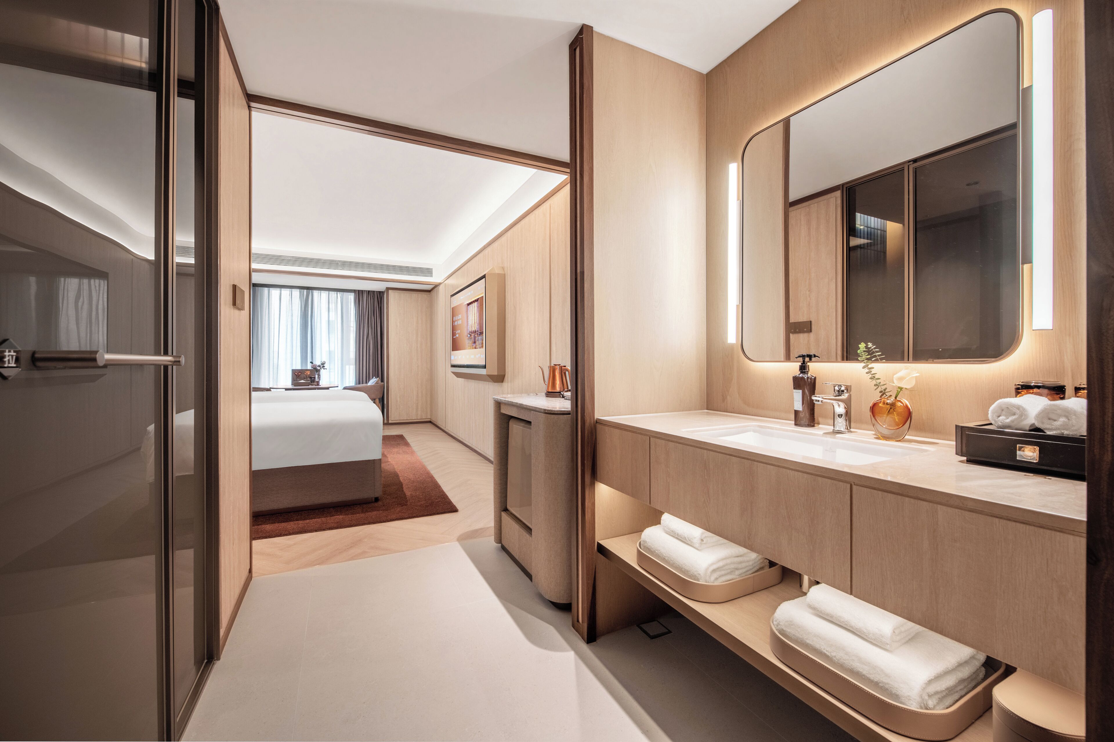 Quarto de hotel moderno com uma cama grande, um banheiro com espelho e um closet espaçoso.