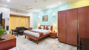 Quarto com cama, escrivaninha, cadeira, guarda-roupa e ventoinha no teto.