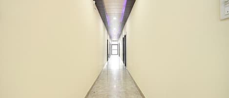 Um corredor comprido e estreito, com piso lustroso e teto com luminária embutida.