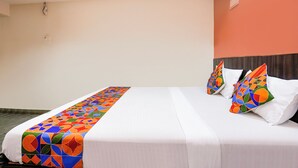 Quarto de hotel com cama, almofadas e cabeceira colorida.