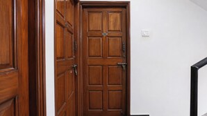 Uma porta de madeira com uma placa de número, uma escadaria e uma parede branca.