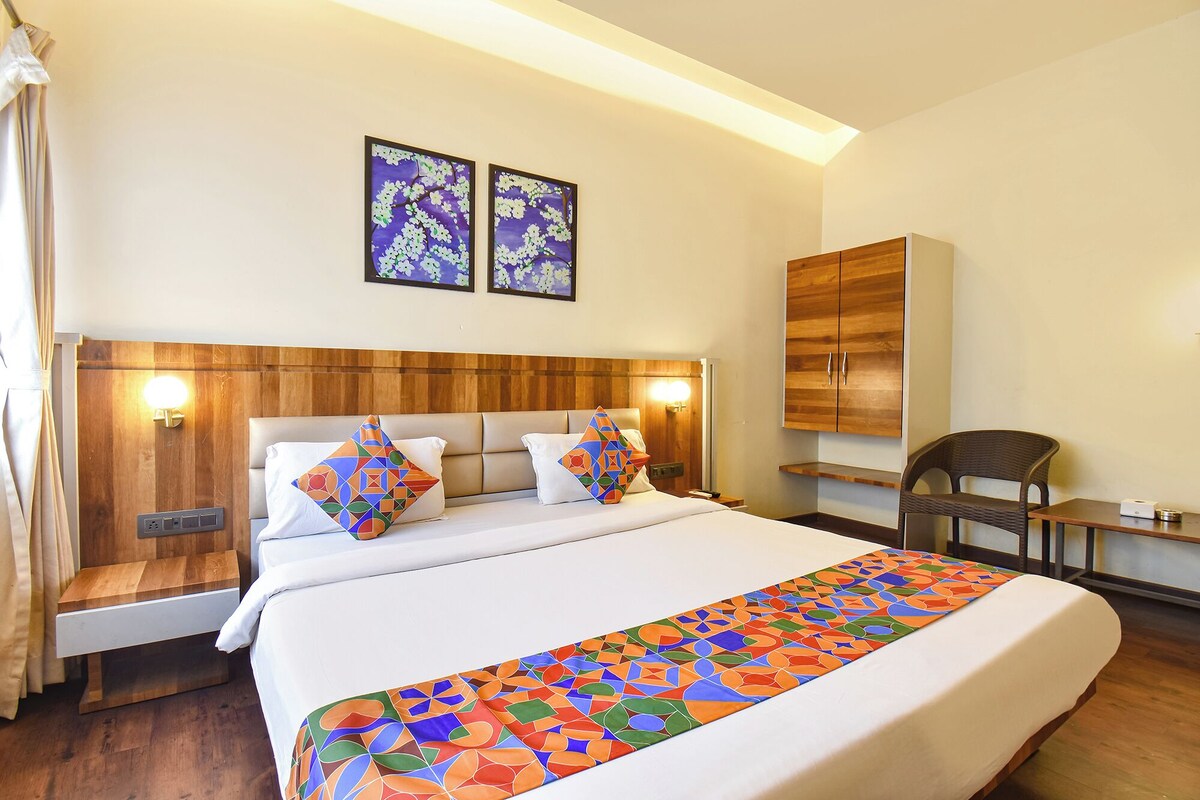 Quarto de hotel com cama, mesas de cabeceira, um guarda-roupa e duas obras de arte penduradas na parede.