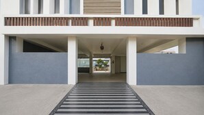 Entrada de um edifício com galeria coberta, colunas e vista para o interior.