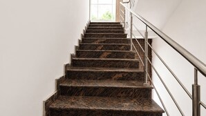 Escada com corrimão de metal e degraus de madeira que levam a um espaço interior iluminado.