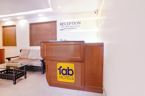 Uma área de recepção com uma mesa de madeira, um sofá e uma placa da Fab Hotels.