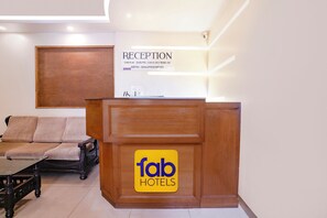 Uma receção com uma placa a indicar horários de entrada e saída, um número GSTIN e o logotipo da Fab Hotels.