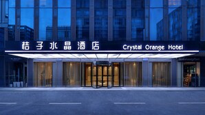 Exterior do Hotel Crystal Orange, com fachada moderna, grande entrada de vidro e sinalização em inglês e outro idioma.