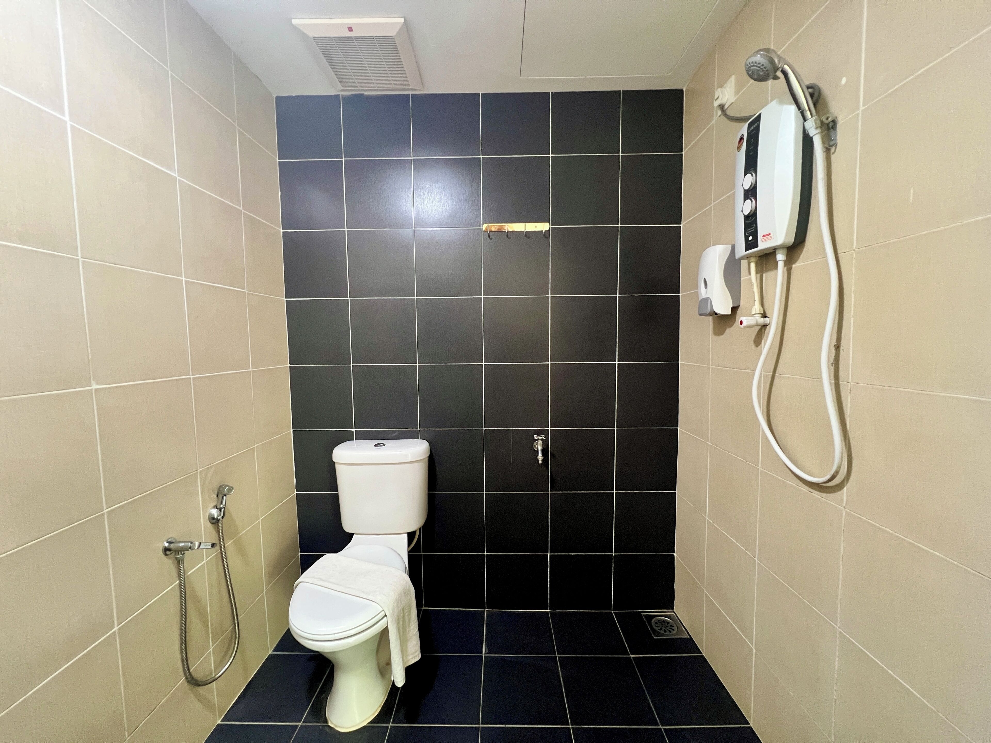 Um banheiro pequeno revestido com azulejos, com vaso sanitário, chuveiro e secador de mãos.