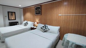 Quarto de hotel com duas camas de solteiro, uma mesa de cabeceira com abajur, parede revestida de madeira e um quadro emoldurado.