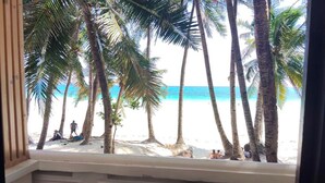 Vista de uma praia com palmeiras e pessoas.