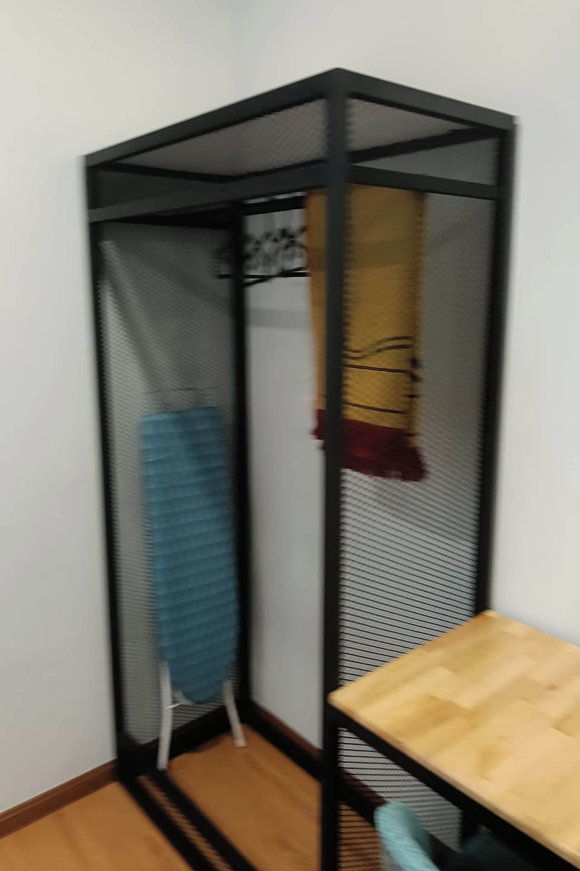 Quarto nos cantos com piso de madeira, divisória de metal preto e uma pequena mesa.