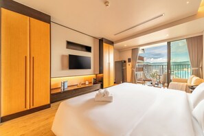 Quarto de hotel moderno com uma cama grande, televisão de tela plana, minibar e varanda com vista para a cidade.