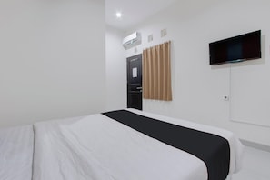 Quarto de hotel com cama, televisão na parede, ar condicionado, guarda-roupa e uma porta.