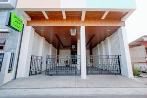 Entrada de um edifício moderno com galeria coberta, portões de metal e uma placa com a inscrição 'URBAN VIEW by Red Decorz'.