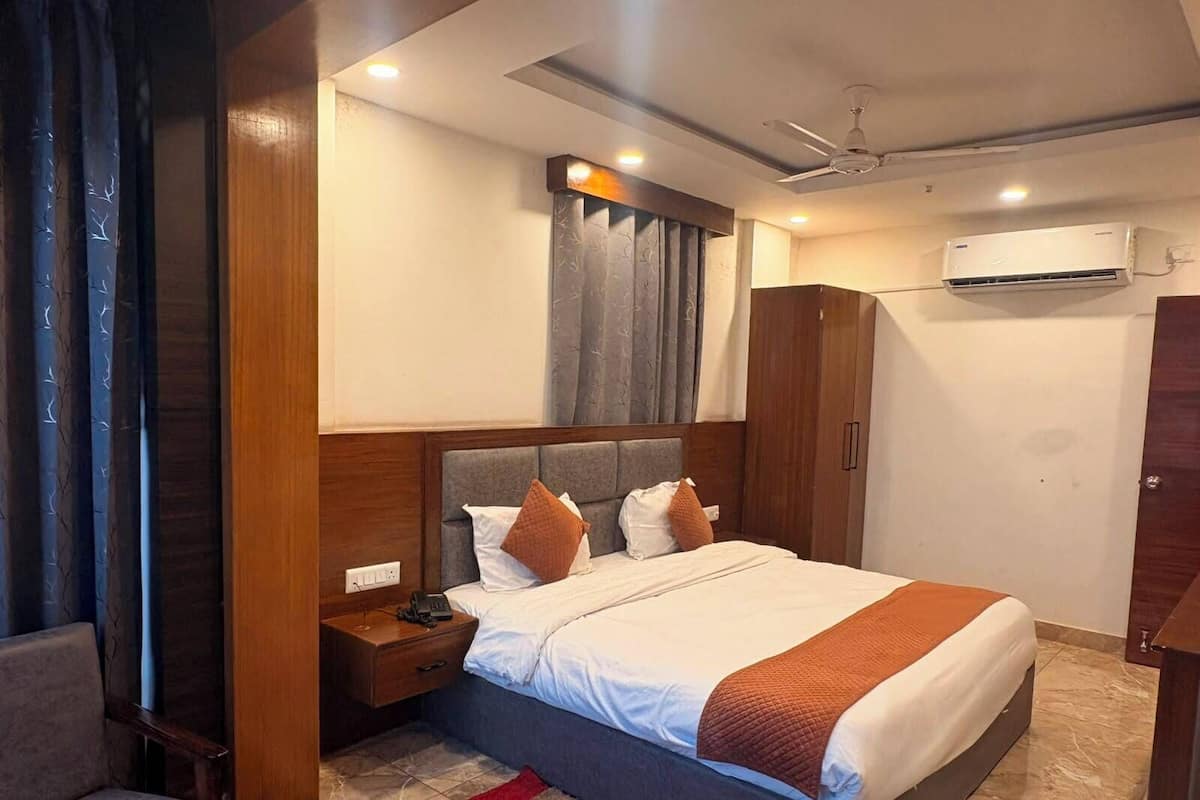 Quarto com cama, mesa de cabeceira, guarda-roupa e ar condicionado.