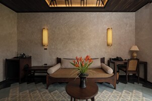 Um hall moderno com um sofá, uma mesa de centro com flores e uma luminária.