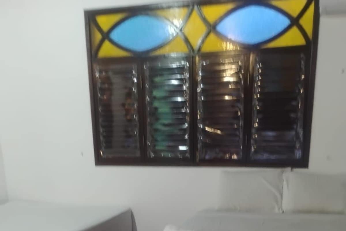 Quarto com duas camas, piso de azulejos e vitral.