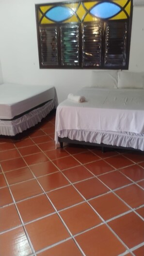 Quarto com duas camas, piso de azulejos e vitral.