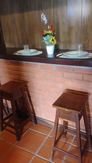 Uma área de bar com dois banquetes, um balcão de madeira e uma parede de tijolos.