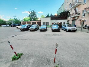 Um estacionamento com vários carros, um edifício com varandas e um céu limpo.