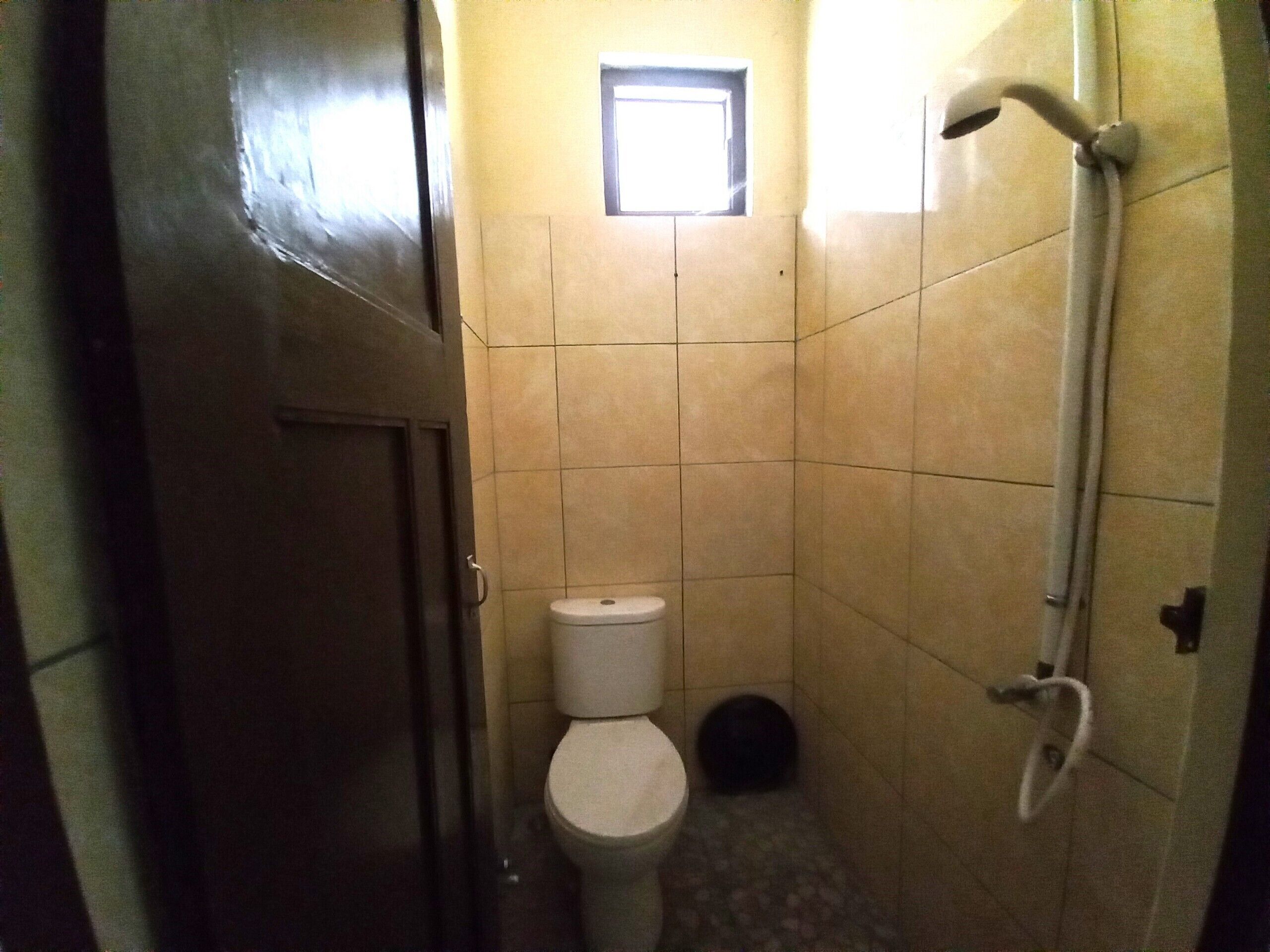 Uma casa de banho pequena com sanita, chuveiro e janela.