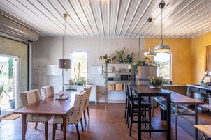 Uma cozinha moderna com área de jantar, apresentando uma mesa de madeira, cadeiras e luminárias pendentes.