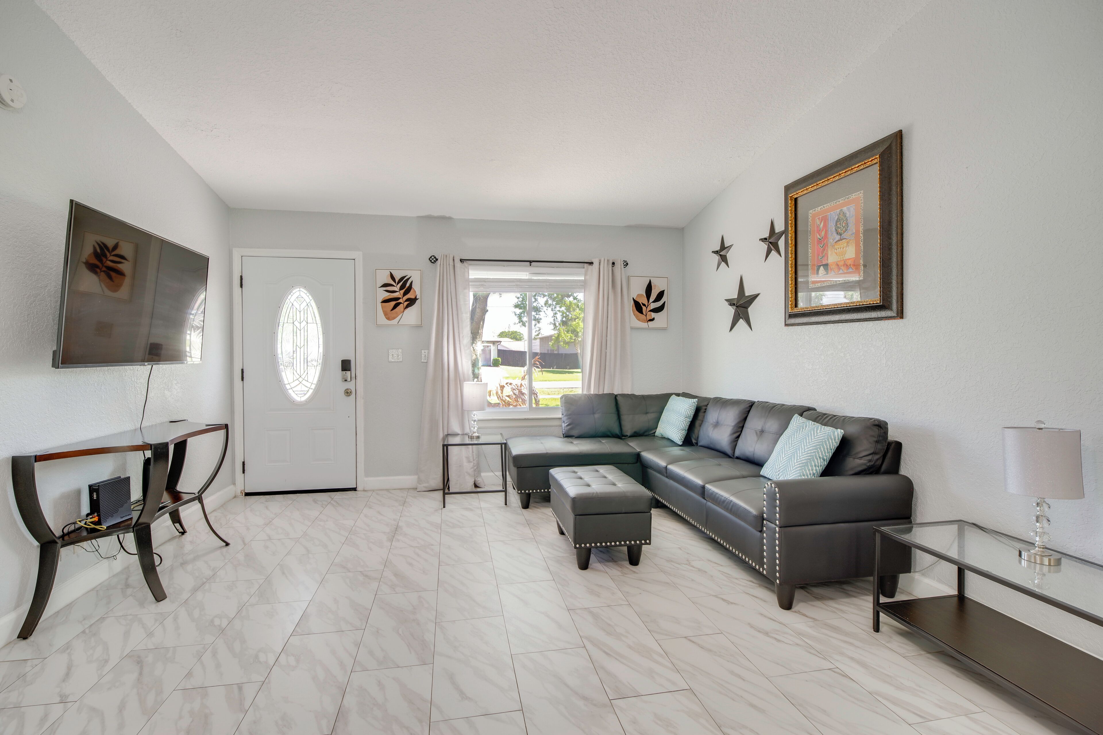 Uma sala de estar com sofá seccional, televisão, mesa de console e porta com janela.