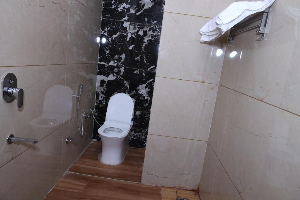 Casa de banho com sanita, chuveiro e porta-toalhas.