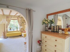 Quarto com cama, penteadeira, espelho e janela com cortinas.