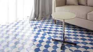 Um quarto com um sofá, uma mesinha redonda e um chão estampado.