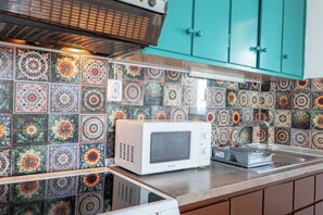 Cozinha com micro-ondas, pia e armários verde-água.