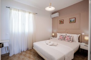 Um quarto bem organizado com uma cama, mesas de cabeceira, uma escrivaninha e uma cadeira.