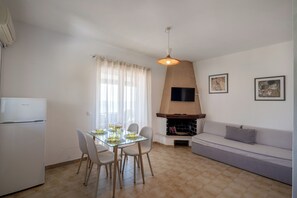 Um espaço compacto com área de refeições, cozinha compacta, sofá e lareira.