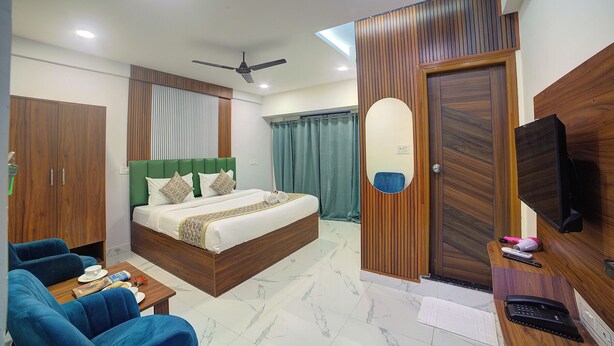 Quarto de hotel com cama, escrivaninha, cadeira, televisão, ventoinha de teto e guarda-roupa.