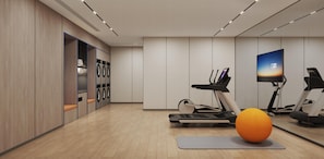 Uma academia moderna com esteira, elíptico, bicicleta ergométrica e uma grande bola de exercício laranja.