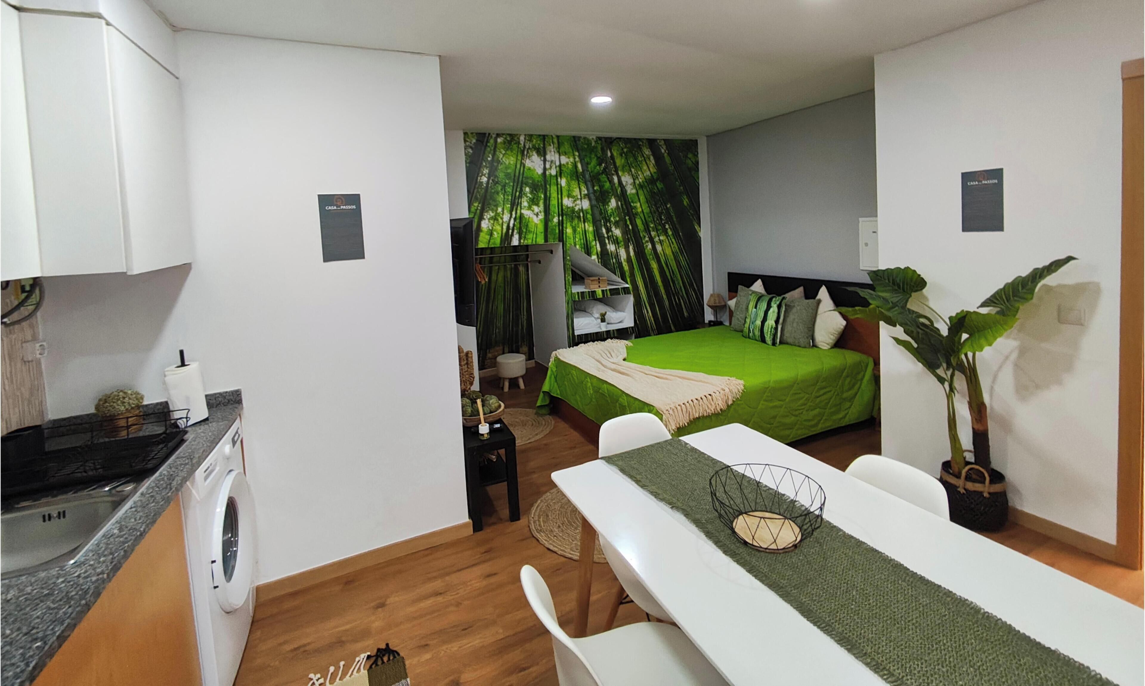 Quarto de hotel pequeno com cama, mesa de jantar, cozinha e banheiro.