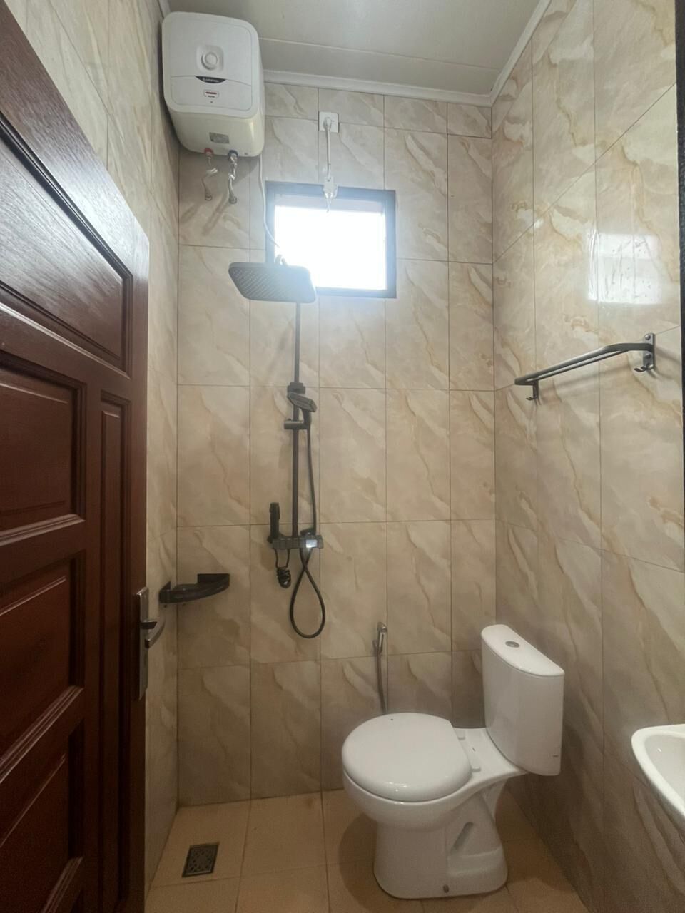 Uma casa de banho pequena com sanita, chuveiro e secador de mãos.