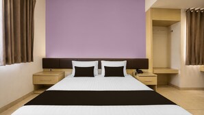 Quarto de hotel com cama grande, duas mesas de cabeceira, guarda-roupa e banheiro.