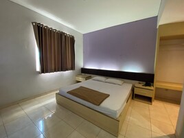 Quarto de hotel com cama, mesas de cabeceira, guarda-roupa e janela com cortinas.