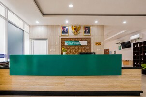 Uma receção com uma cobertura verde, um emblema fixado na parede e um retrato emoldurado acima.