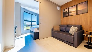 Uma sala de estar moderna com um sofá, uma mesinha e vista através de uma porta de vidro.