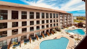 Um hotel com vários andares, piscinas ao ar livre e um terraço coberto.