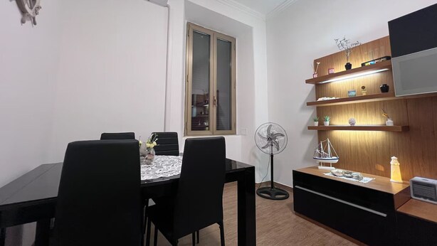 Um espaço de estar compacto com área de refeições, um armário embutido de madeira e um ventilador.