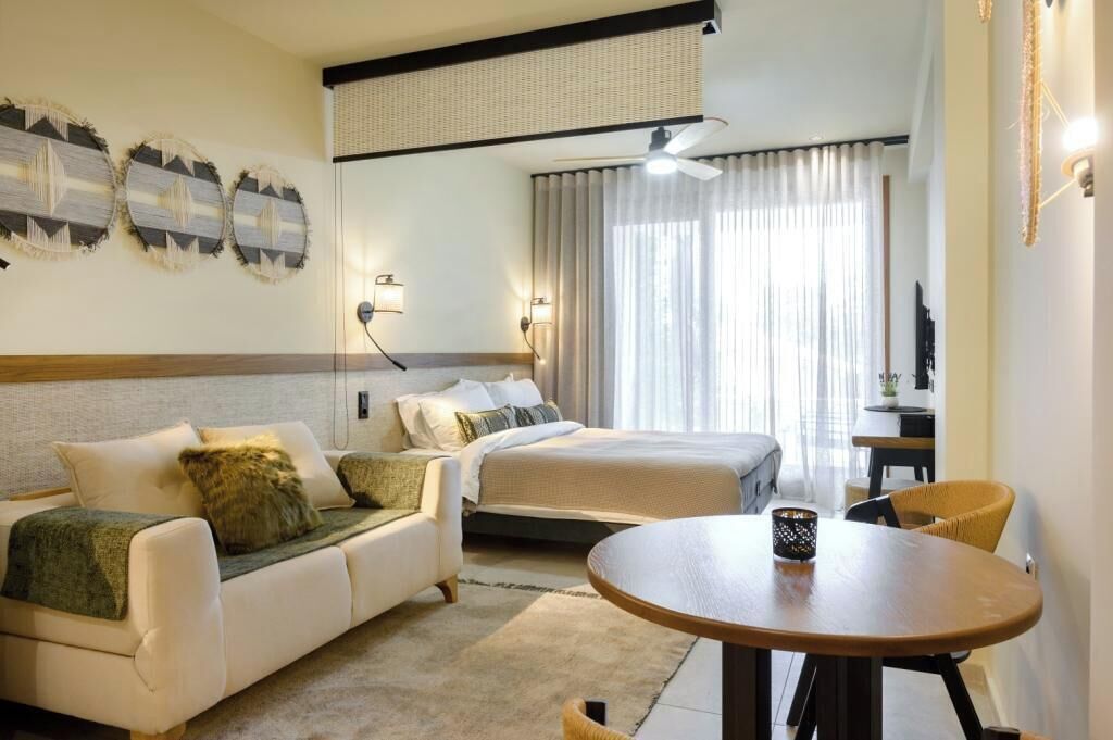 Quarto de hotel com cama, sofá, mesa redonda e ventilador de teto.