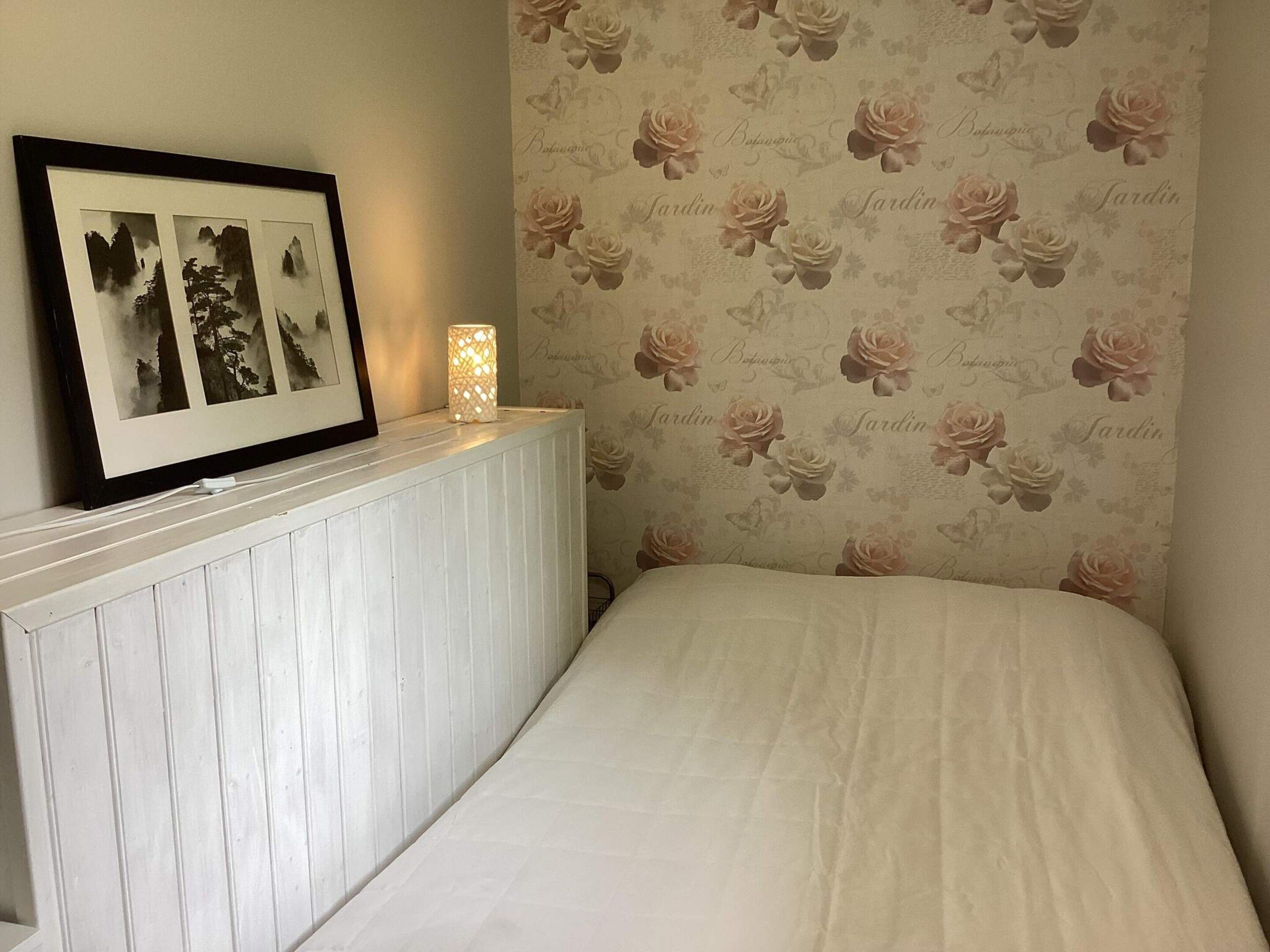 Quarto com cama, quadro emoldurado em um radiador e parede com padrão floral.