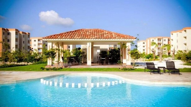 Um hotel com piscina, área de estar externa e um pavilhão coberto.