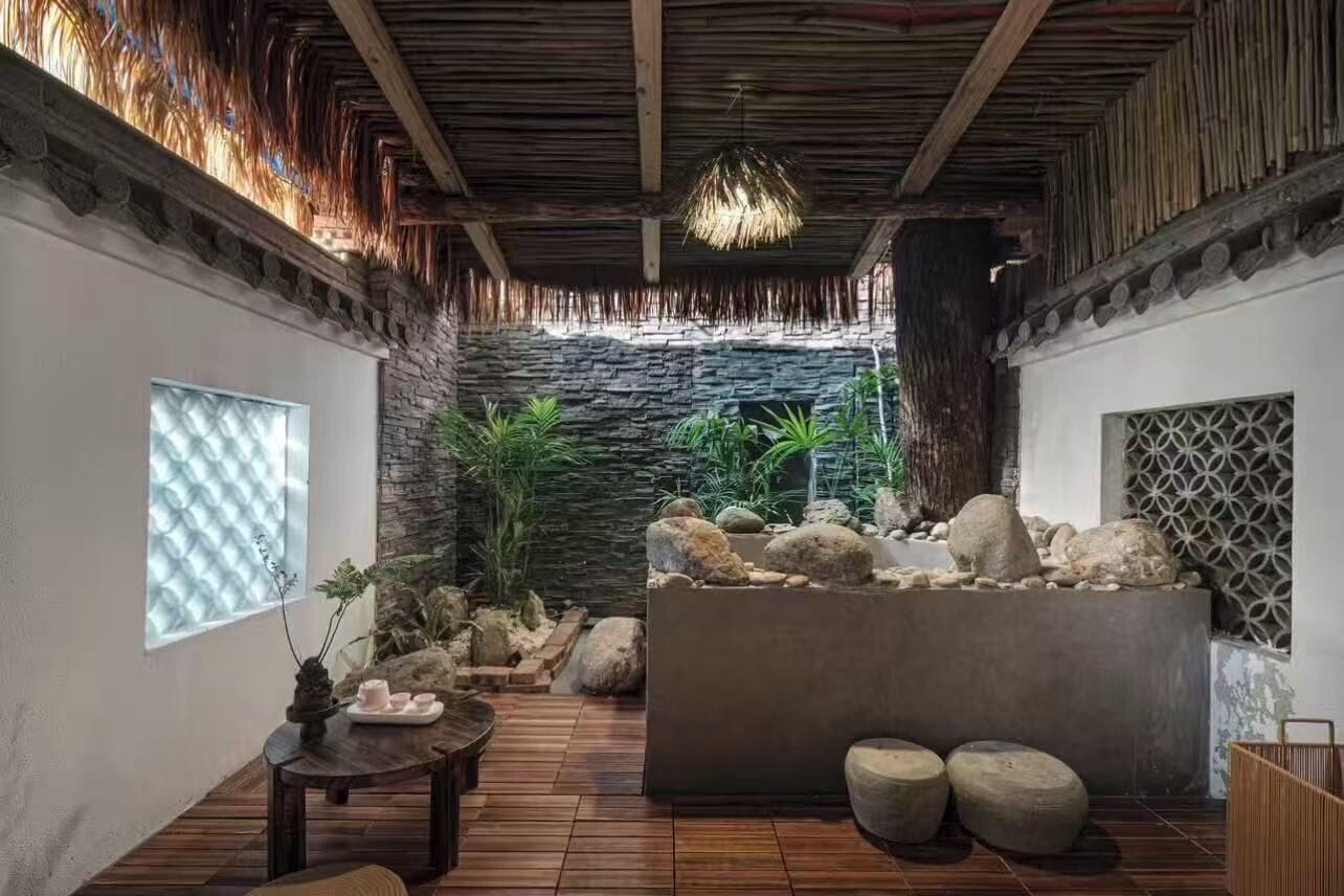 Quarto com parede de pedra, teto de madeira, um pequeno elemento aquático e um espaço de estar.