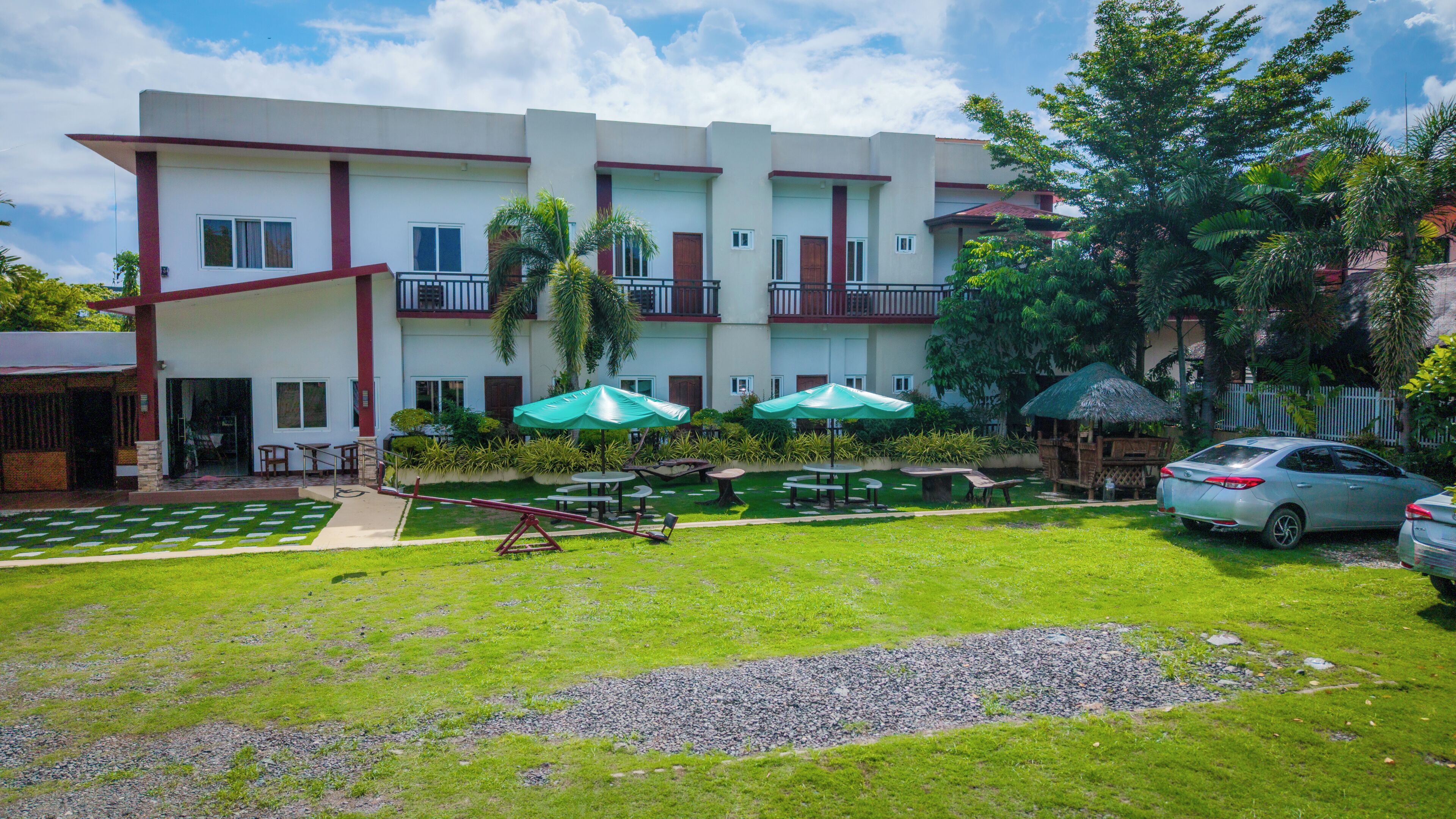 Um hotel de vários andares com um pátio que inclui área de estar ao ar livre, piscina e um carro estacionado nas proximidades.