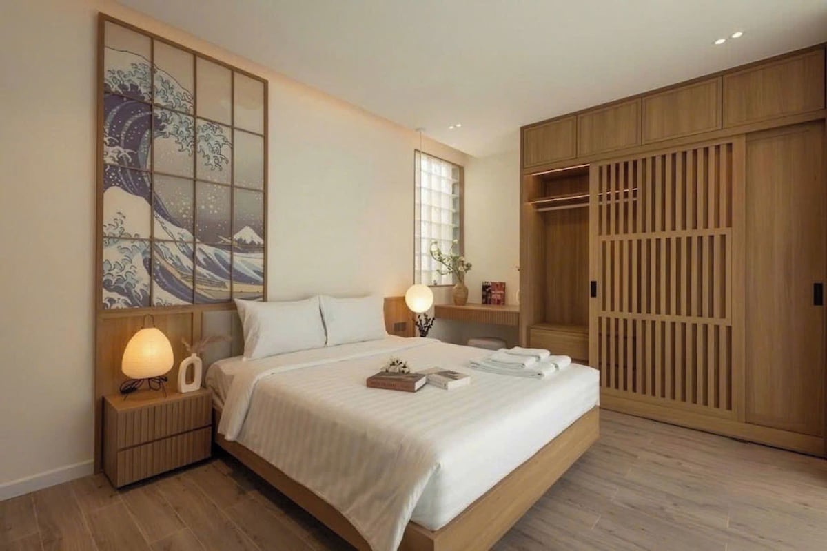 Quarto de hotel com uma cama grande, uma porta japonesa tradicional deslizante e uma obra de arte na parede.